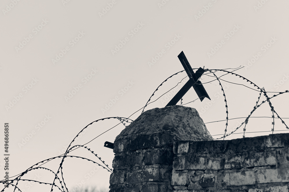 Barbed wire is stretched on the old brick fence, the metal support for ...