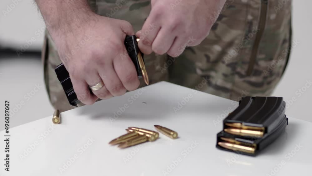 A man close up loading a machine gun clip with ammunition. Preparation ...