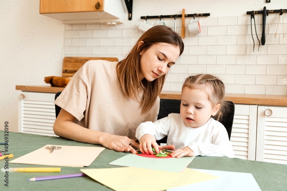 Young mother helping cute daughter with art and craft project in home ...