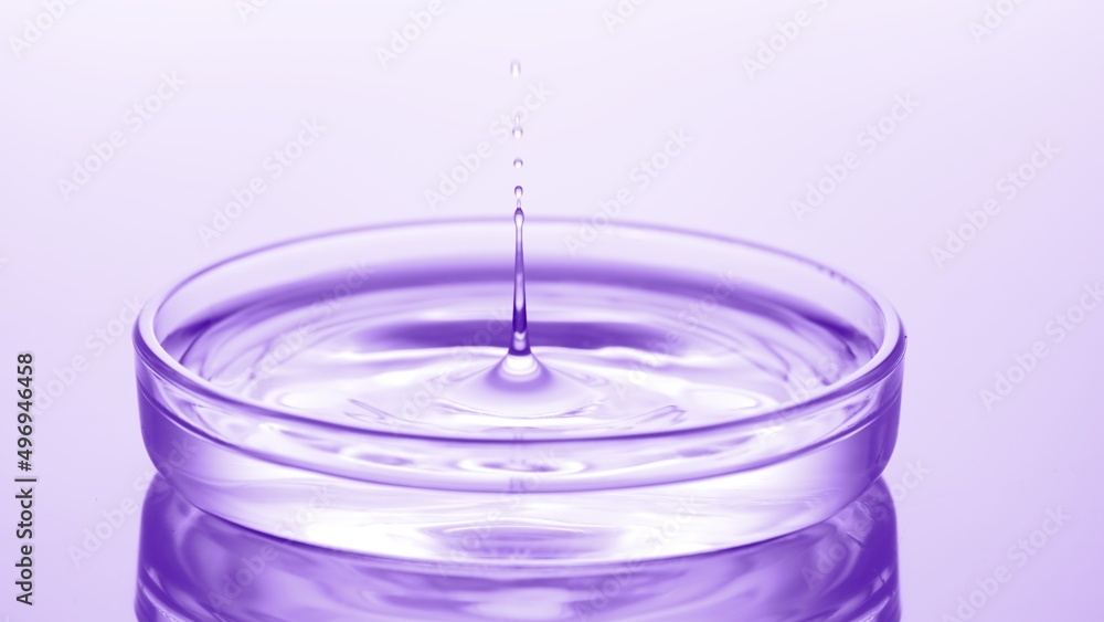 Drop of water falls down into petri dish with clear fluid creating ...