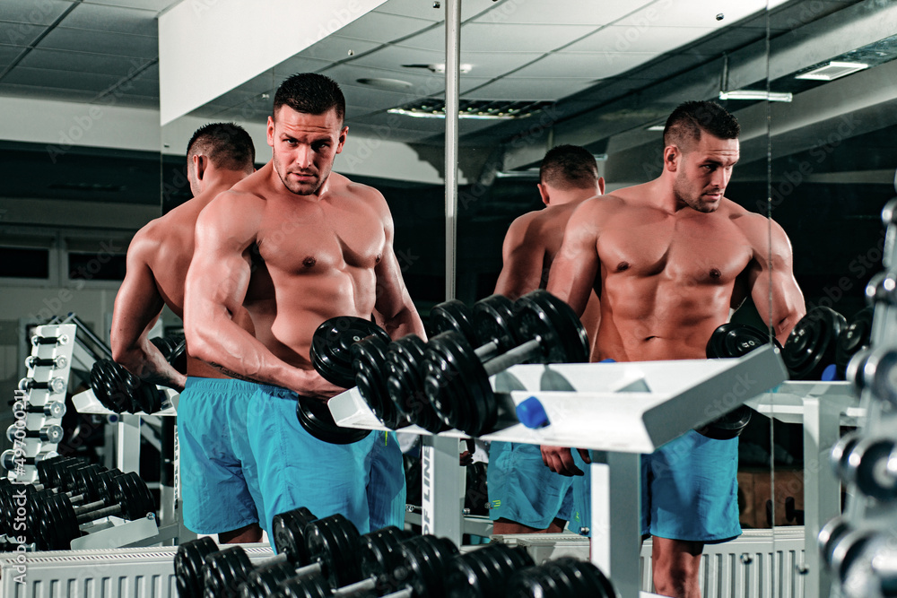 Muscular man working out in gym doing exercise for biceps with ...