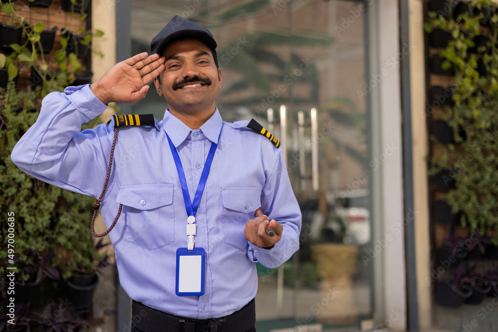 Portrait of security guard saluting while working at gate Stock Photo ...