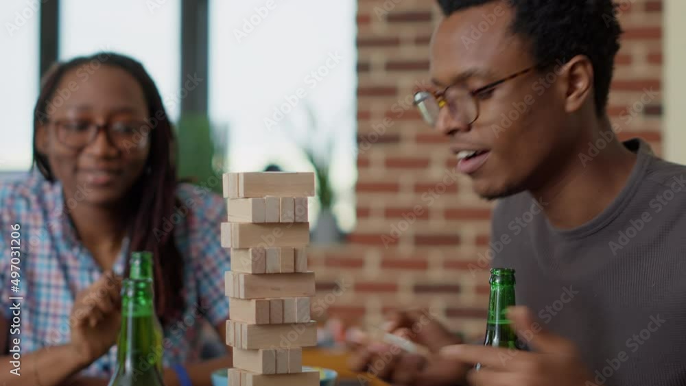 Group of cheerful people having fun with jenga wooden tower, enjoying ...
