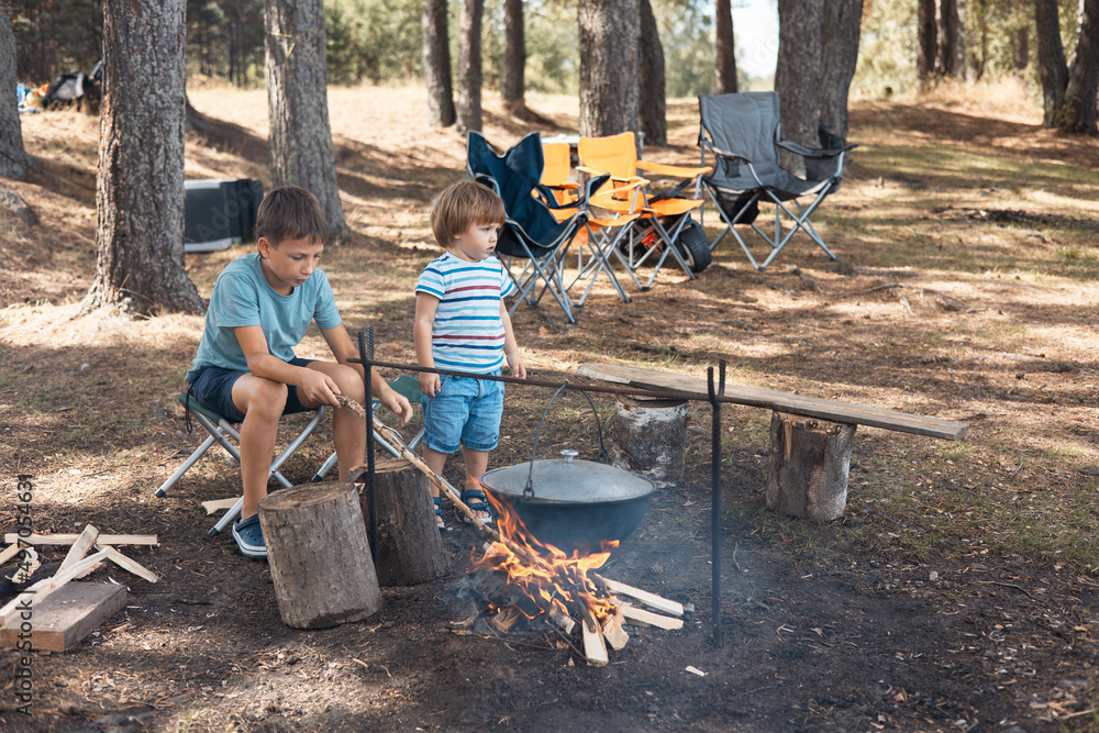 Foto de Children sitting around a campfire in forest in summer. Family ...
