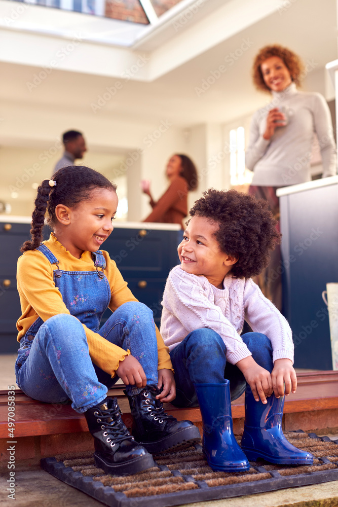 Foto de Children Sitting On Step At Home Putting On Boots Before Going ...