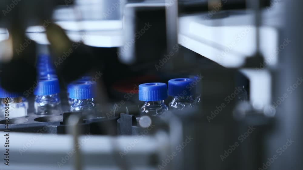 Scientist puts glass vial with blue cap into HPLC Autosampler at ...