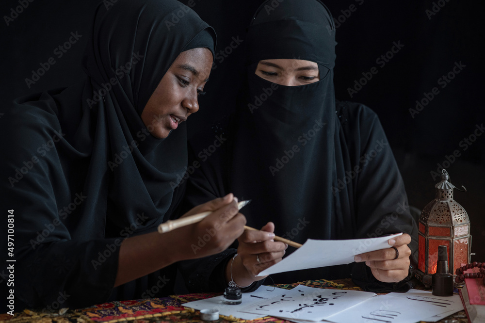 Muslim women wearing black hijab learn to writing Arabic calligraphy ...