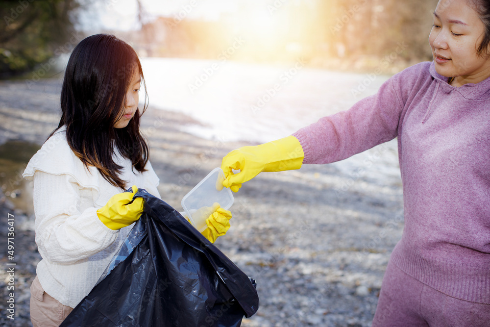 Earth Day concept, Woman and daughter pick up garbage in litter bags ...