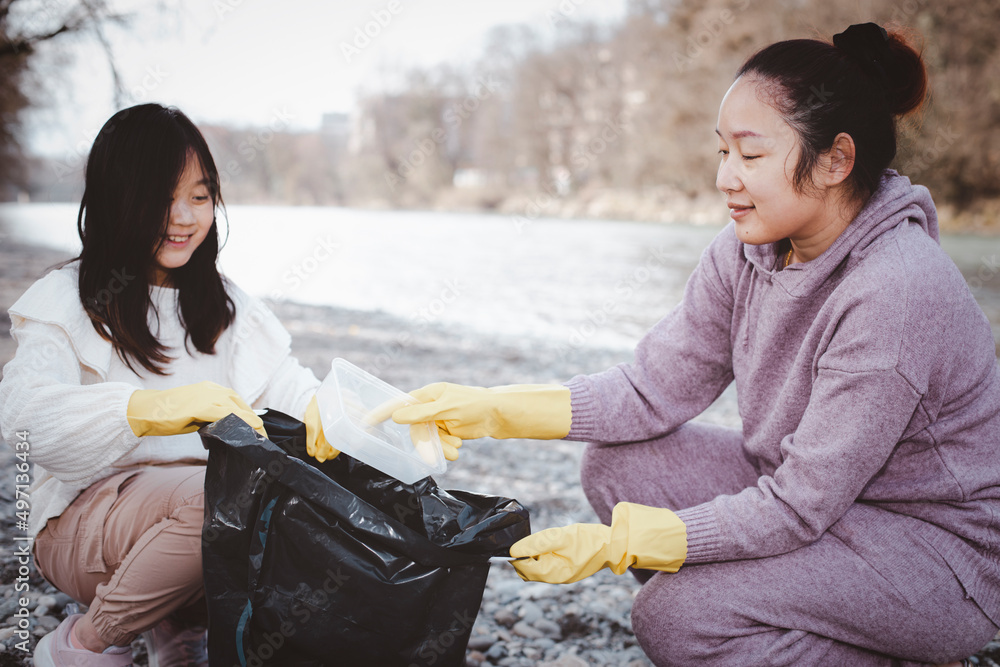 Earth Day concept, Woman and daughter pick up garbage in litter bags ...