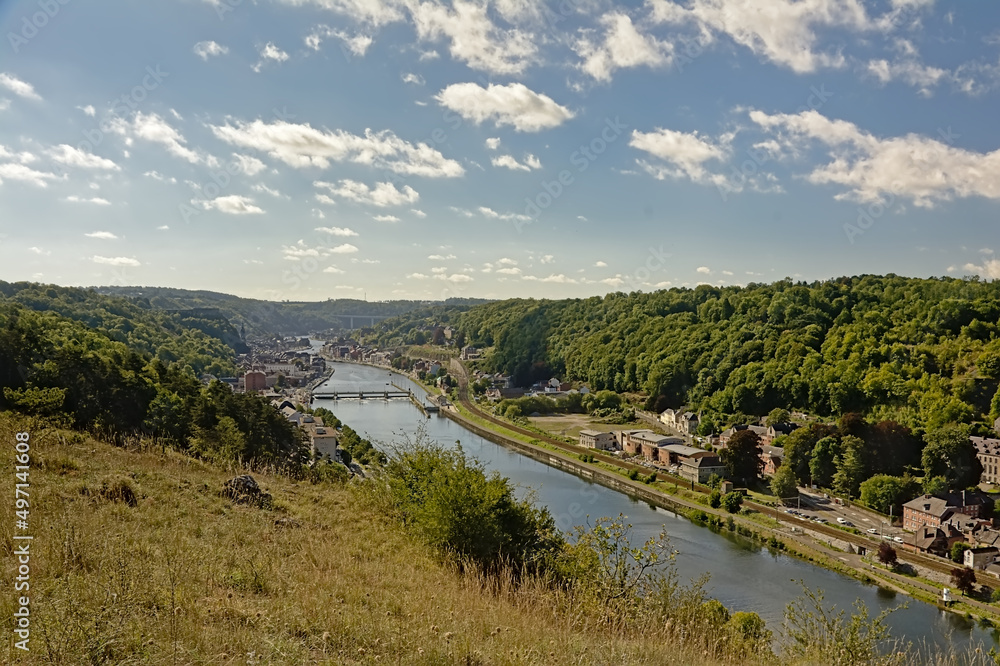 River Meuse with sluice, surrounded by hills with forests and houses on ...