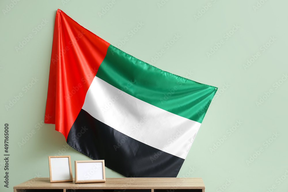 Blank frames on table and UAE flag hanging on green wall Stock Photo ...