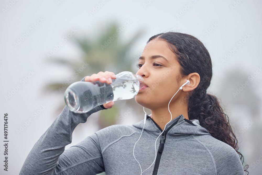 Dont forget to keep yourself hydrated. Shot of a young woman drinking ...