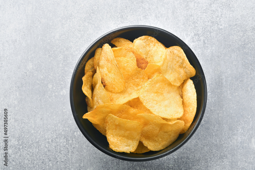 Fotka „Potato chips. Fast food. Crispy potato chips ceramic black bowl ...
