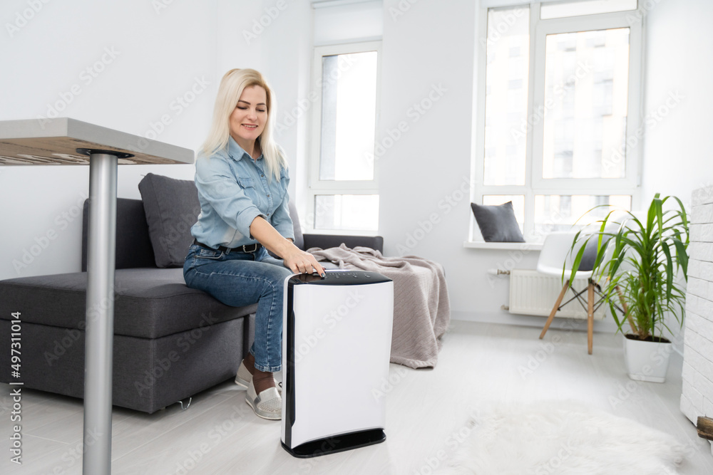 woman turning on and using the modern air purifier in the living room ...