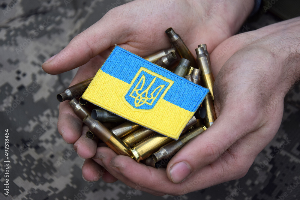 Dirty male hands hold a pile of shell casings with a Ukrainian passport ...