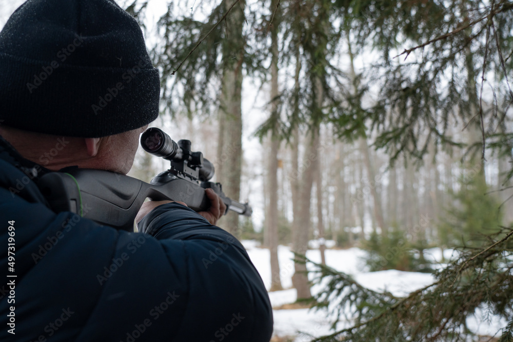 A man with a rifle in the spring forest, the hunter holds a rifle and ...