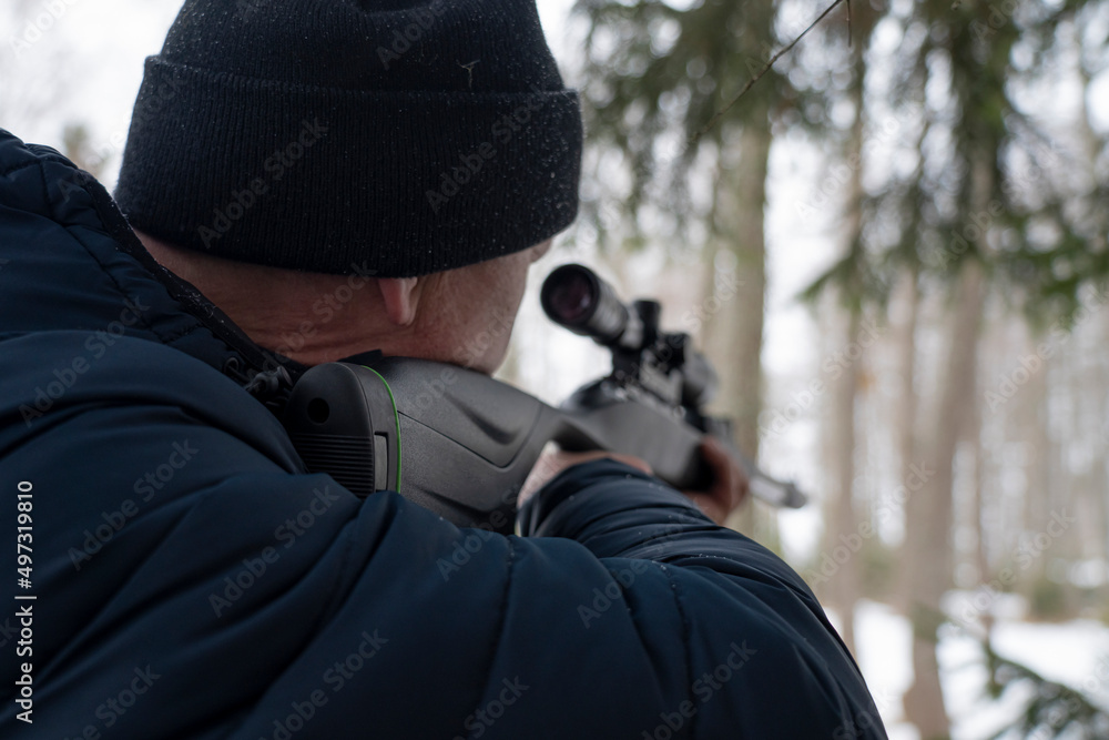 A man with a rifle in the spring forest, the hunter holds a rifle and ...