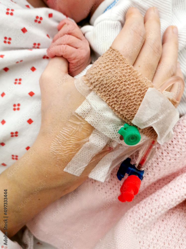 Woman holding her newborn baby with peripheral venous catheter on her ...