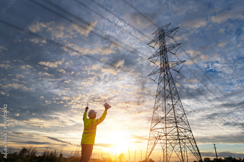 Engineer inspecting high voltage tower with radio,Engineer inspecting ...
