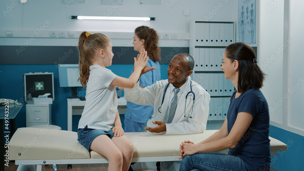 Friendly doctor giving highfive to cheerful child at checkup visit in ...