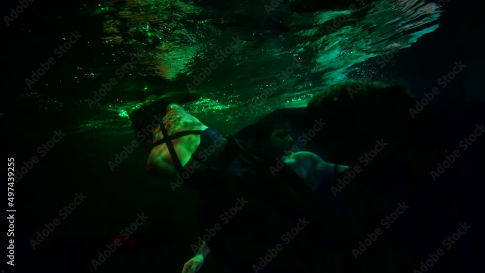 enigmatic water nymphs are floating around adult handsome man in dark ...