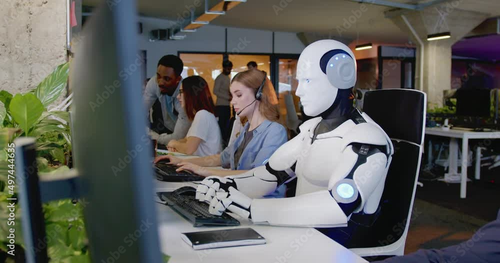 Robot working at computer among people. Android typing on keyboard in ...