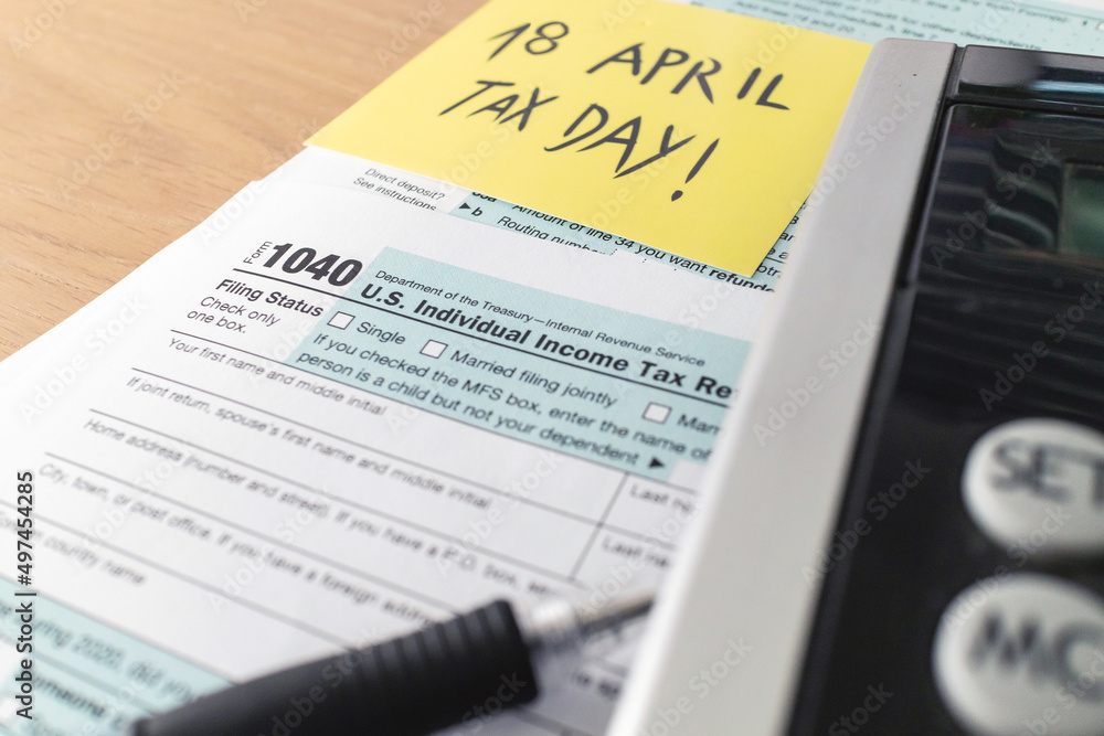 18 April 2022 Tax Day 1040 form with calculator and pen on table. Stock ...