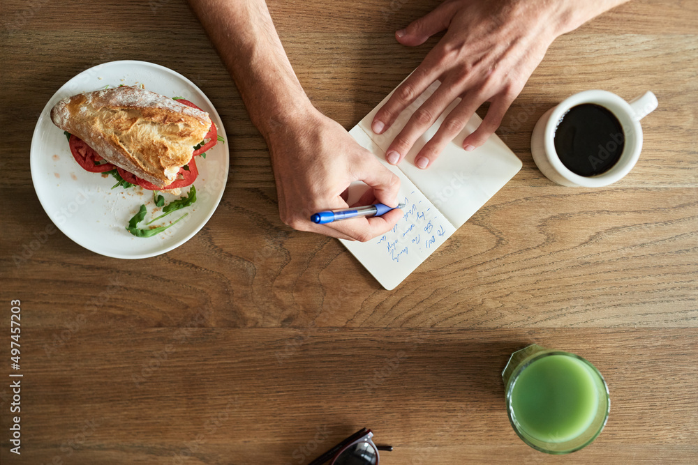 Person writing plan while having meal. Anonymous person writing To Do ...