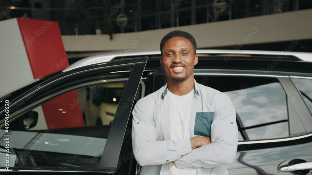 African american car dealership principal standing in vehicle showroom ...