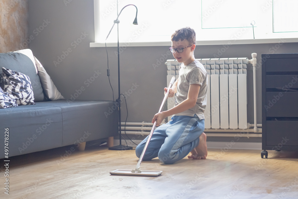 A teenage boy cleans the floor with a mop in the room, a teenage ...