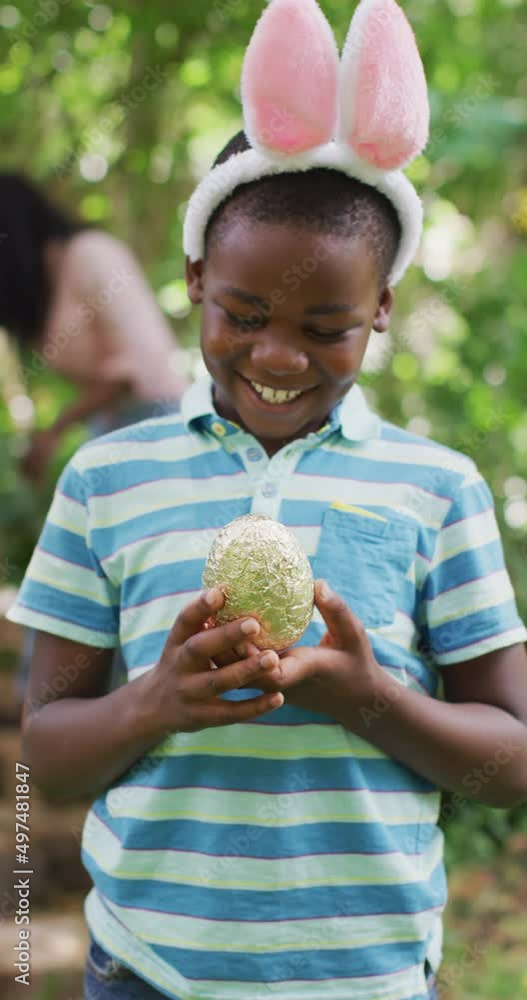 Vertical video of portrait of happy african american boy with egg at ...