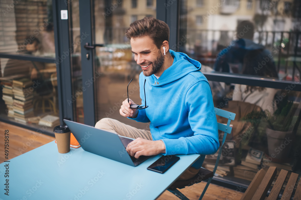 Smiling male freelancer browsing funny video content while networking ...