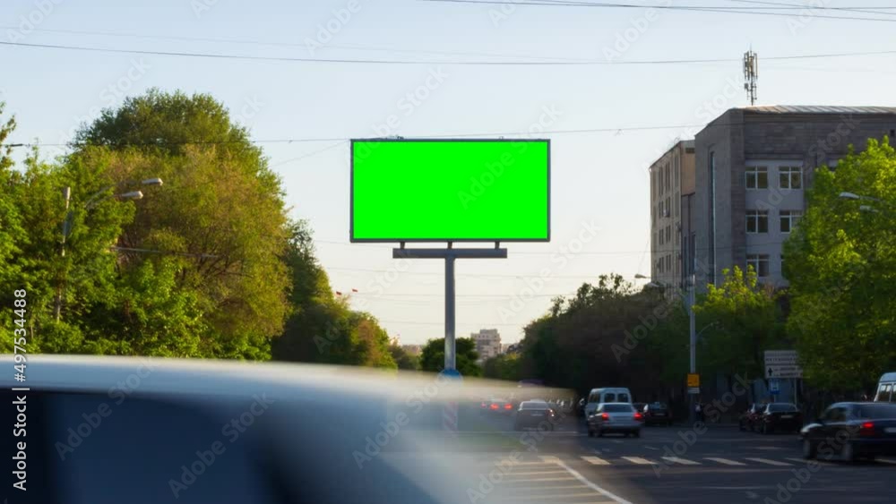 A billboard with green screen on a background of urban traffic with ...