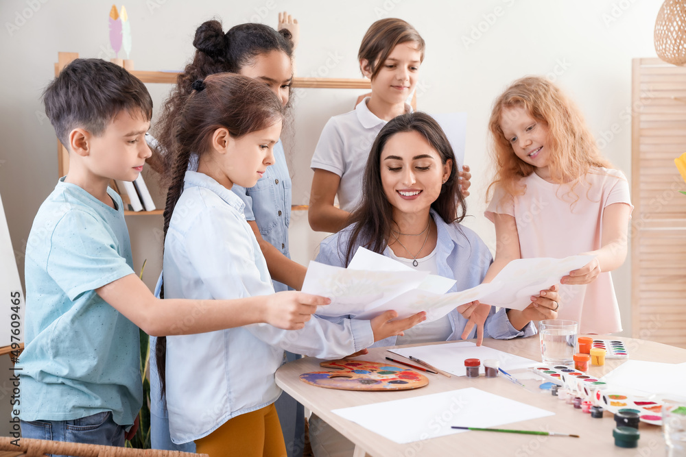 Cute children showing teacher their pictures painted during master ...