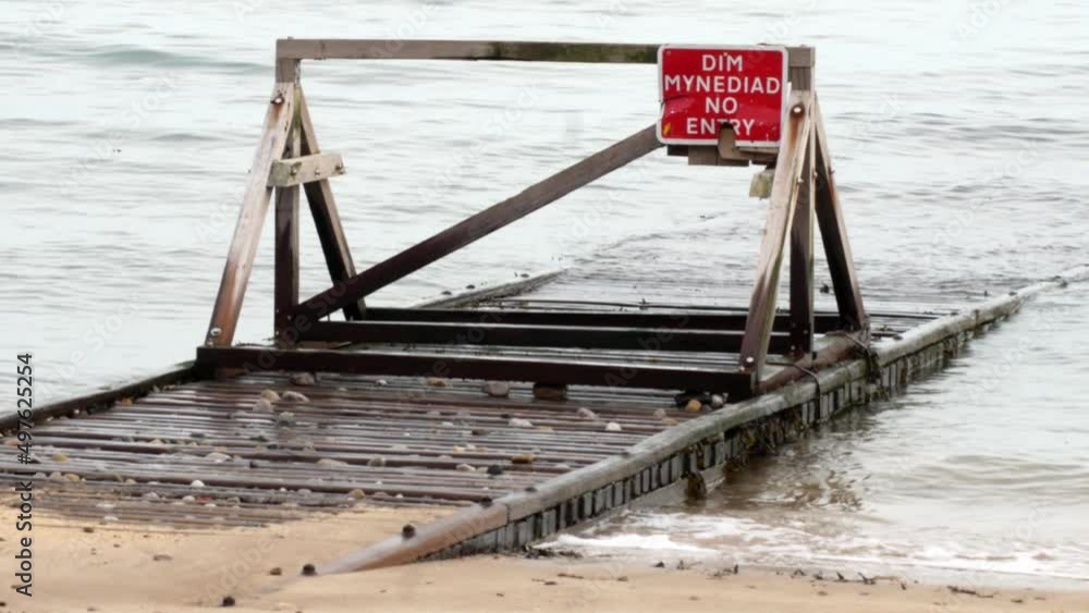 Tide in on flooded seaside wooden plank walkway jetty with Welsh ...
