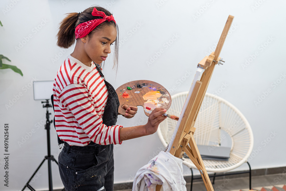 Black woman painting on easel in art studio Stock Photo | Adobe Stock