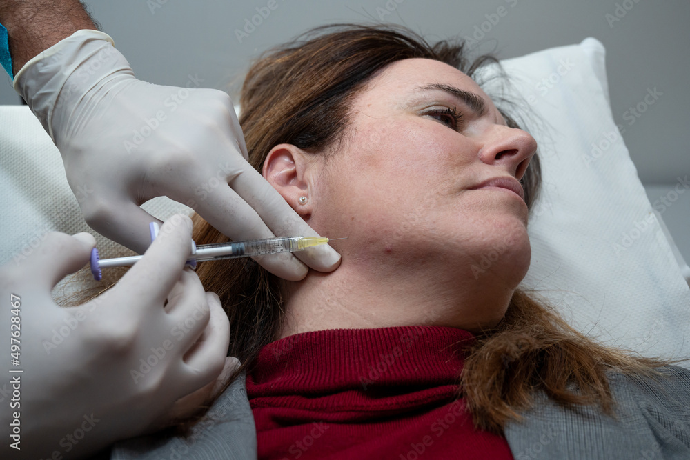 Crop doctor doing jawline injection to female client Stock Photo ...