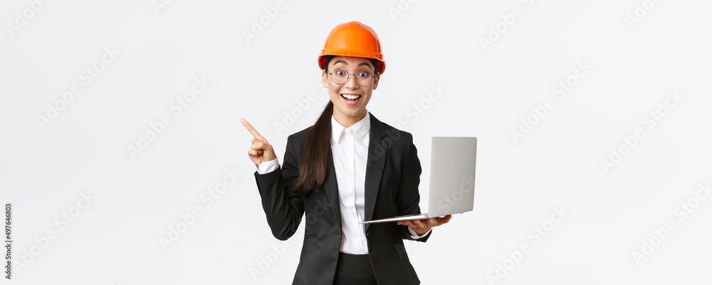 Excited happy asian female engineer, industrial woman in safety helmet ...
