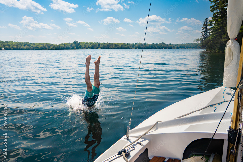 Diving Into Lake from Dinghy Sailboat Anchored on Cottage Lake Stock ...