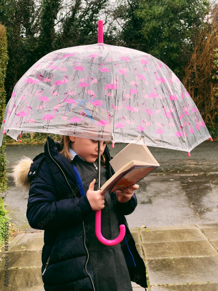 Little girl reading a book while outdoors on a rainy daY foto de Stock ...
