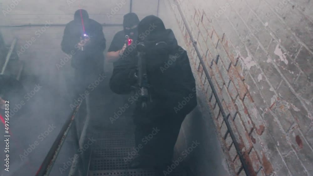 A special forces swat team ascends a stairwell with guns and laser ...
