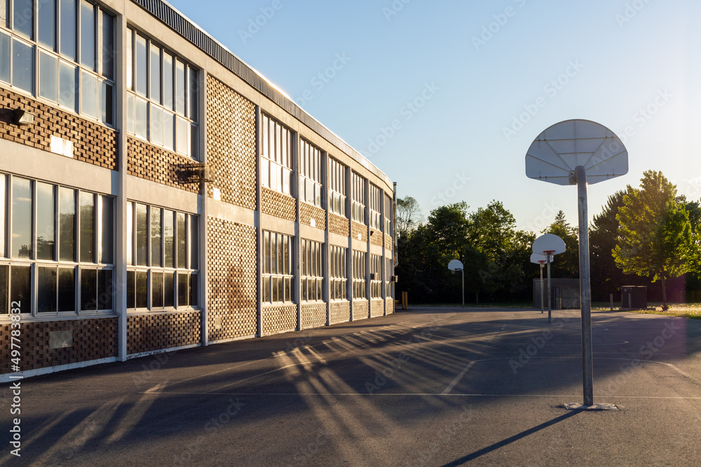 School building exterior and school yard with basketball court in the ...
