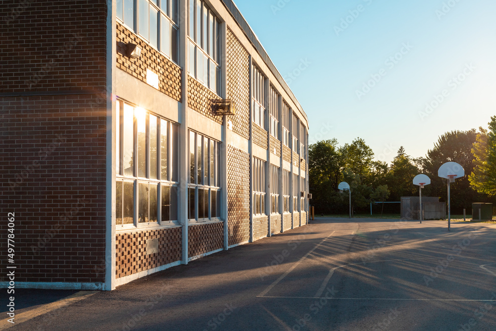 The exterior of the school building and school yard with a basketball ...