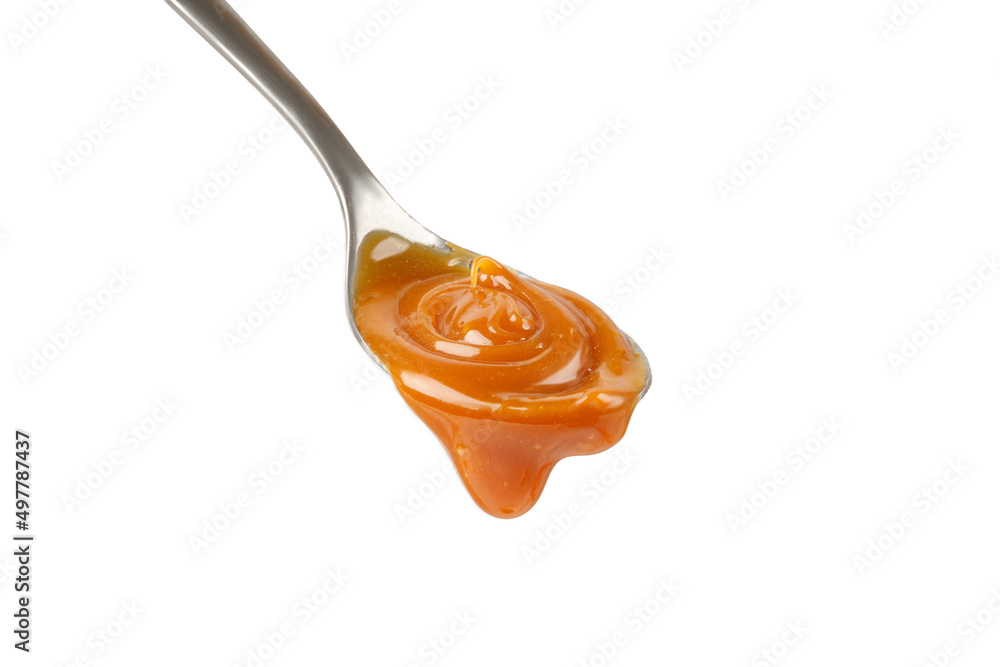 Liquid caramel on spoon. Caramel drips from the spoon. Pouring sweet ...