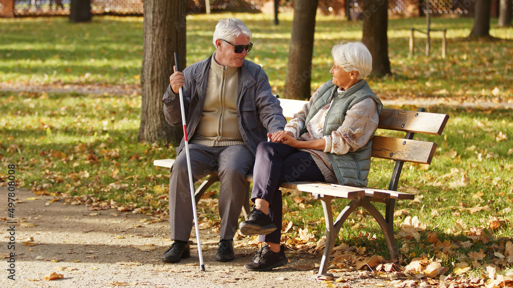 Aged Caucasian married people sit on the bench looking at each other ...