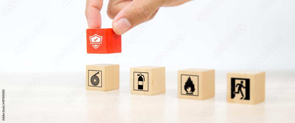 Hand choose cube wooden block stack with fire icon and door exit sing ...