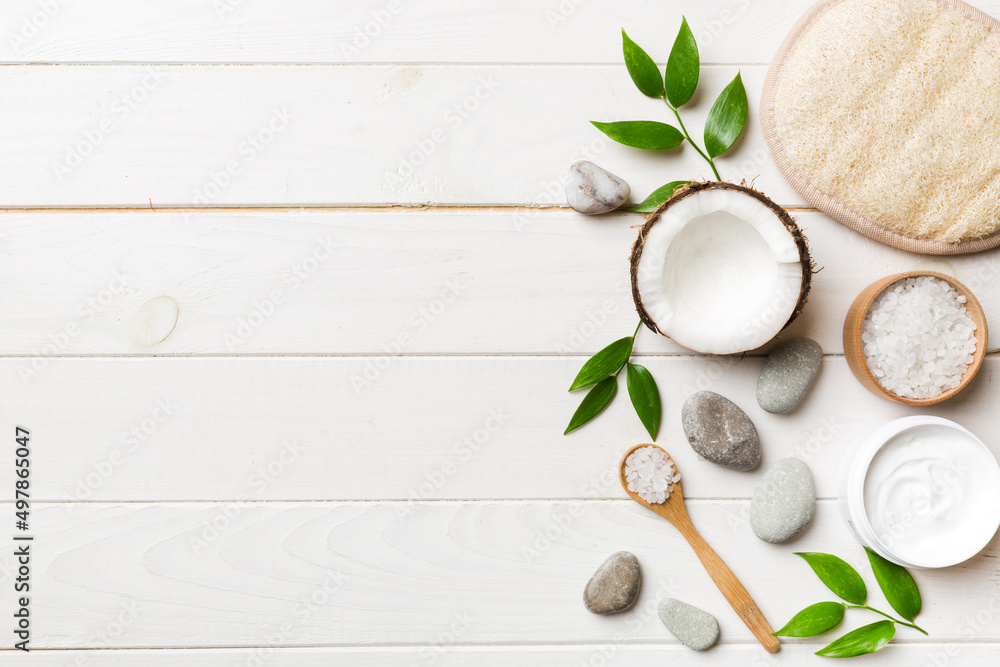 Coconut with jars of coconut oil and cosmetic cream on colored ...