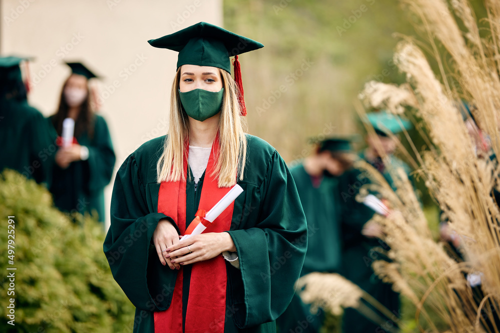 University student in graduation gown holds her diploma on graduation ...
