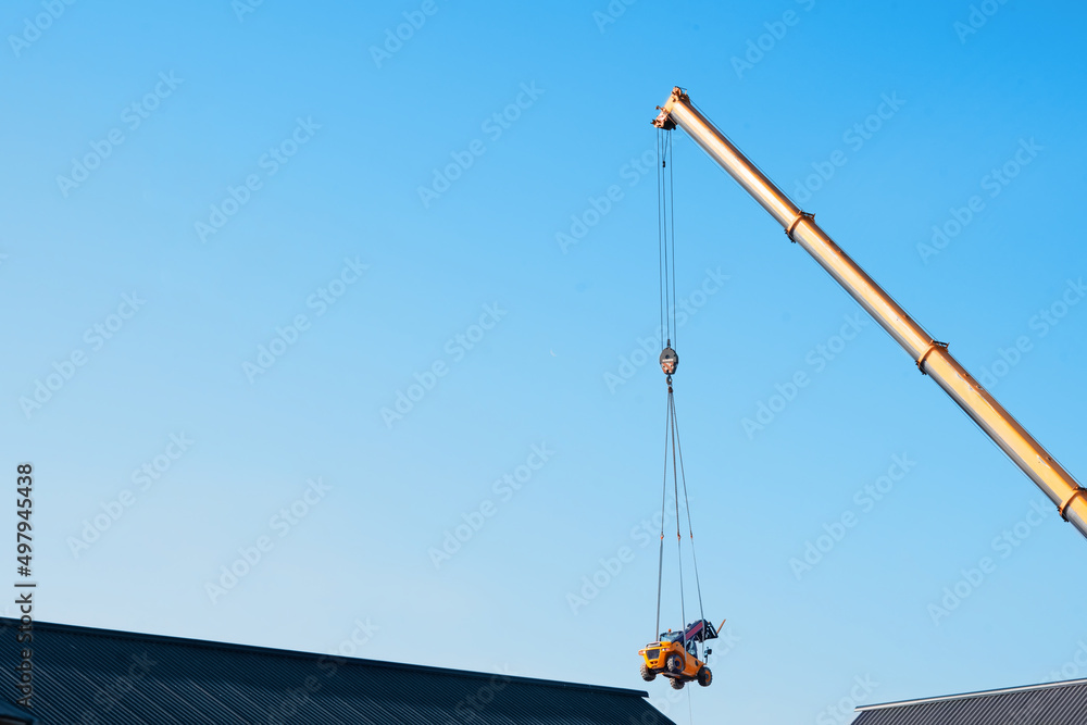 Mobile crane lifting telehandler above the building to place it in the ...