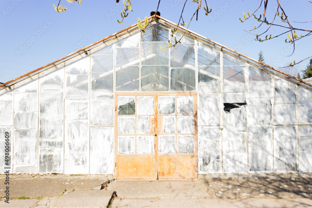 Old destroyed greenhouse with broken window glasses and rusty door ...